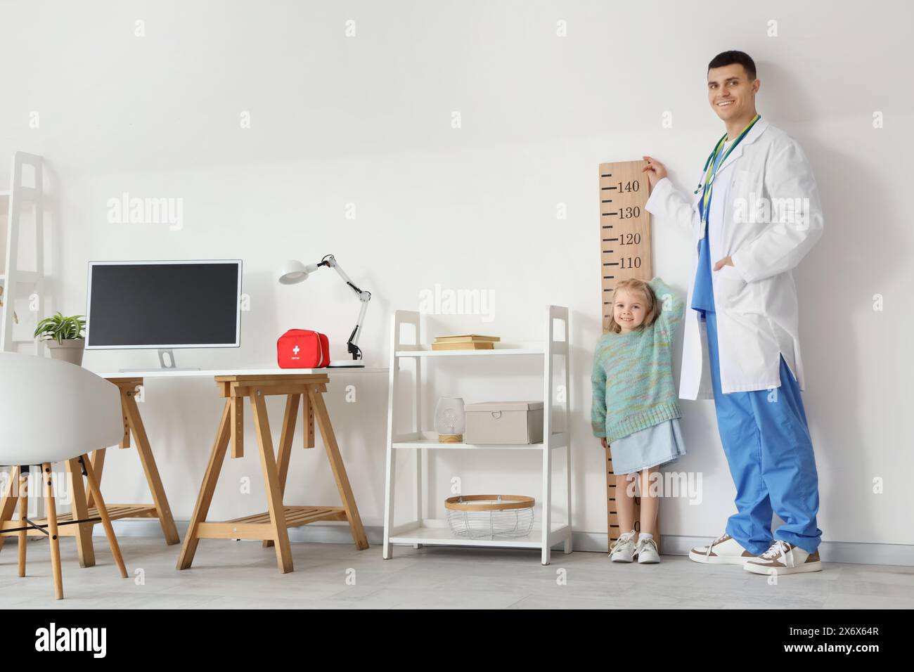 Male pediatrician measuring height of little girl in clinic Stock Photo ...