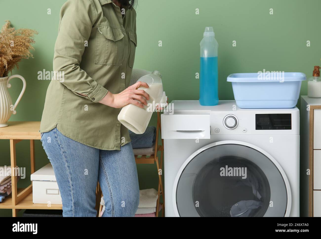 Woman pouring detergent into washing machine in laundry room Stock ...
