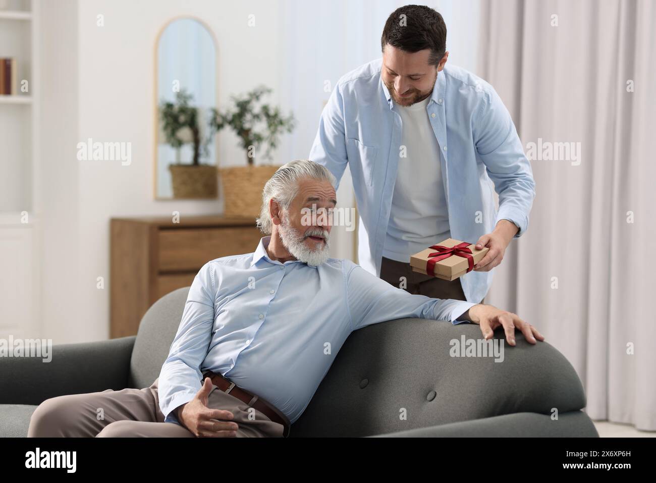 Son giving gift box to his dad at home Stock Photo - Alamy