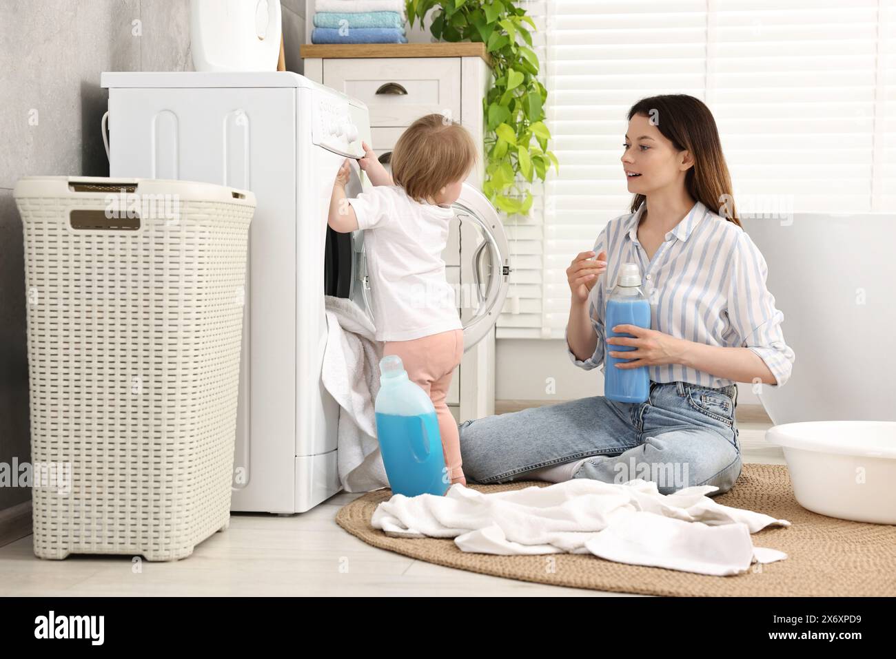 Mother with her daughter washing baby clothes in bathroom Stock Photo ...