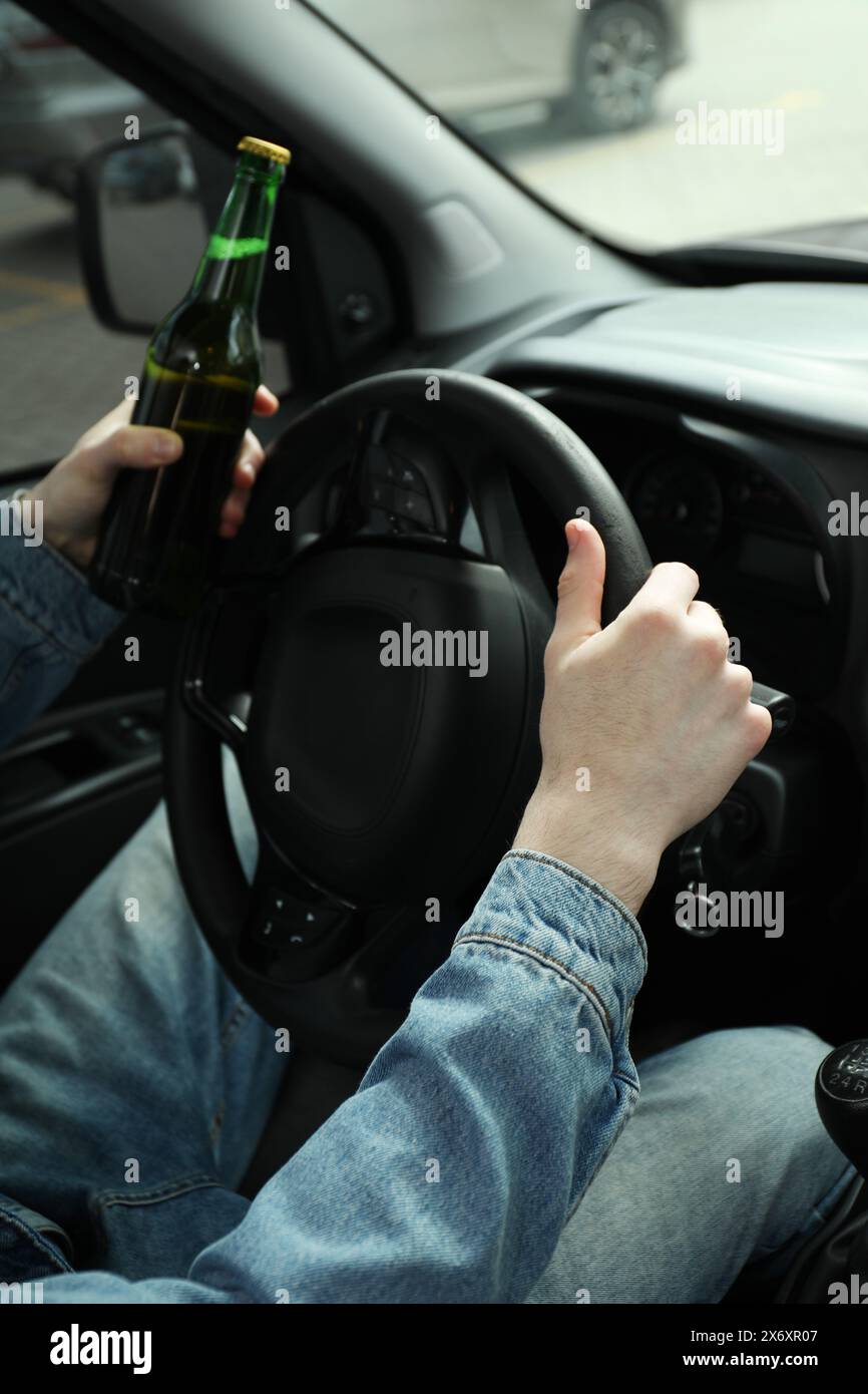 Man with bottle of beer driving car, closeup. Don't drink and drive ...