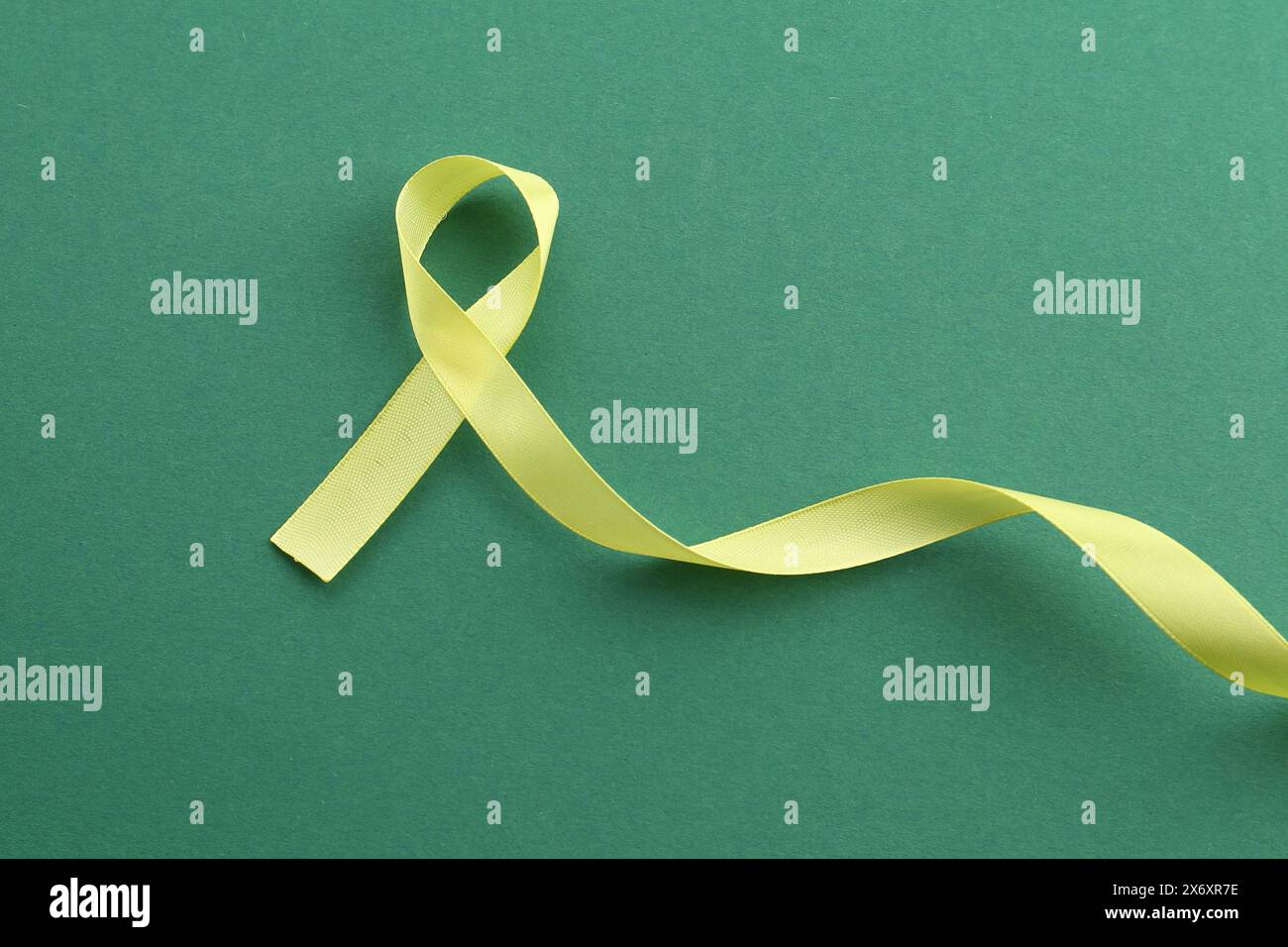 Yellow awareness ribbon on green background, top view Stock Photo - Alamy