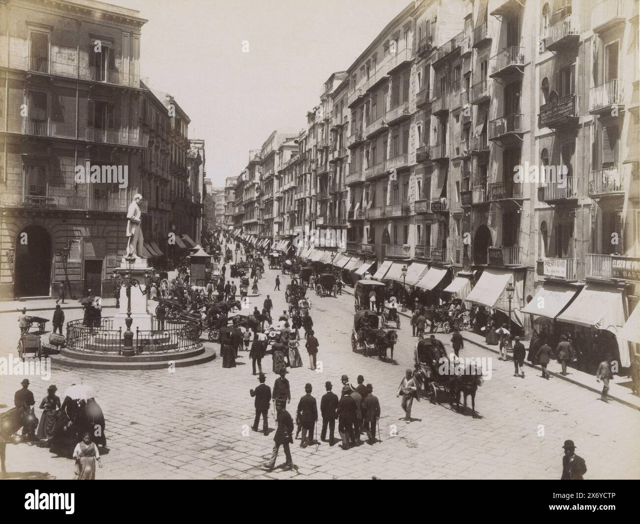 View of the Via Roma in Naples with a statue, shops, horse-drawn ...