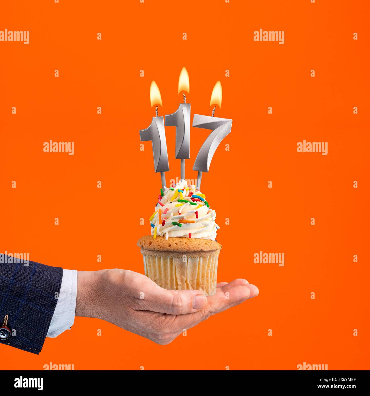 Hand holding birthday cupcake with number 117 candle - background ...