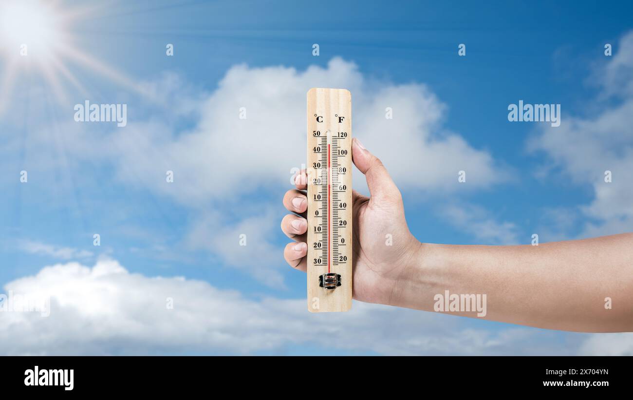 Human hand holding thermometer with hot temperature with a sky ...