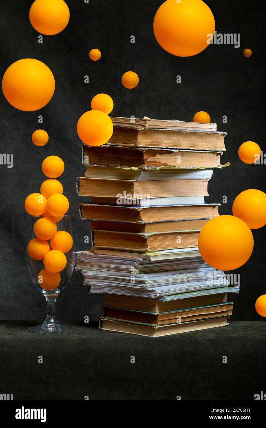 Still life with a stack of books and orange balloons Stock Photo - Alamy