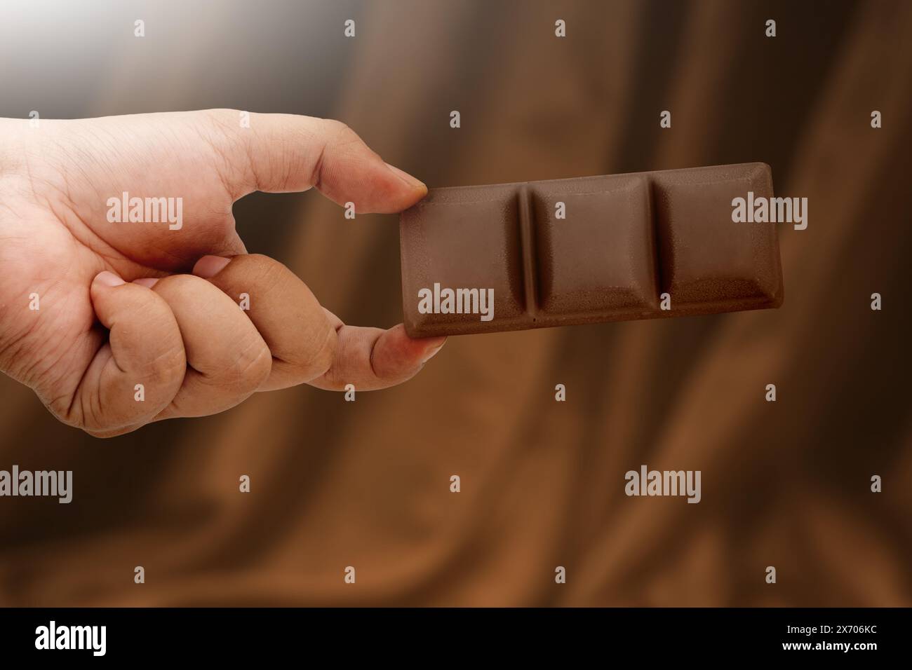 Close up human hand holding chocolate bar, concept of giving on world ...