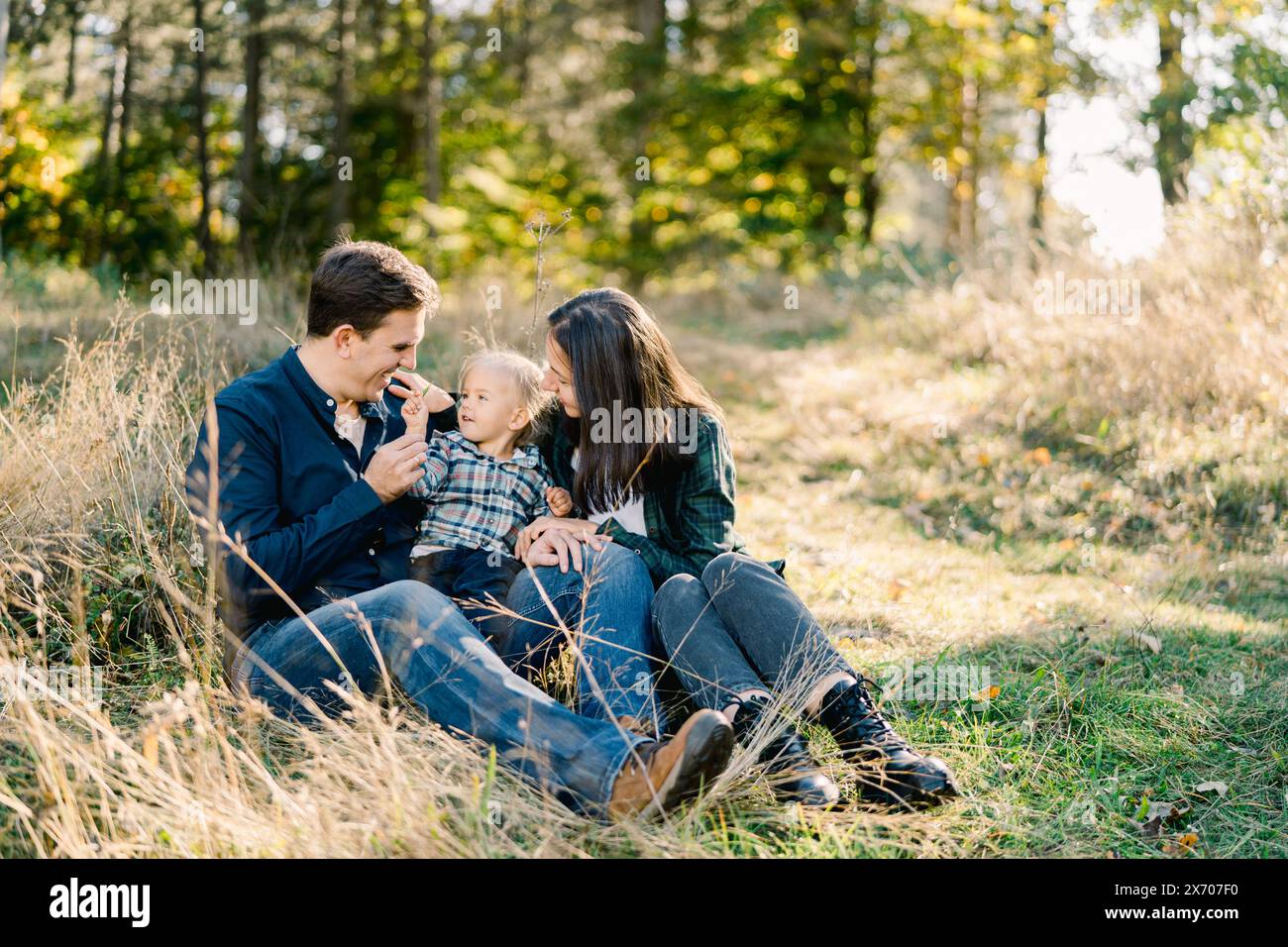 Mom hugs dad with a little girl sitting on his lap in a clearing Stock Photo - Alamy
