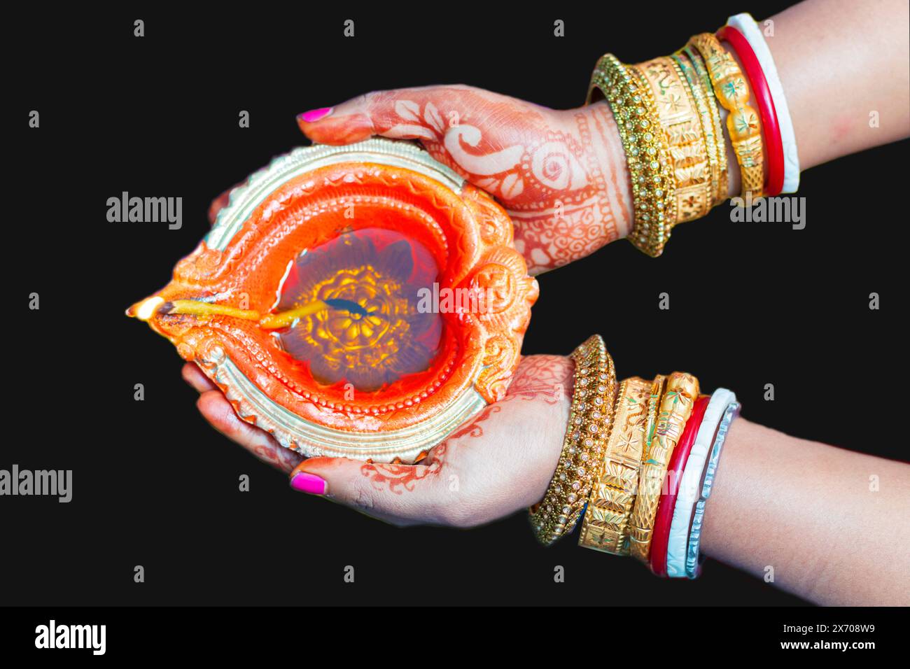 an Indian lady hands holding candle lit diya with black background ...