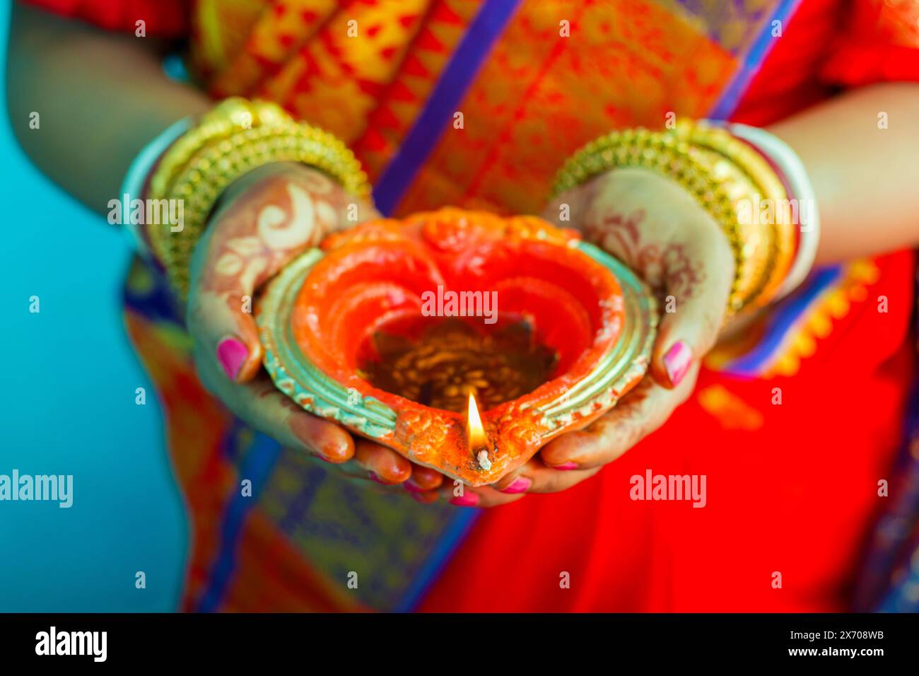 an Indian lady hands holding candle lit diya with black background ...