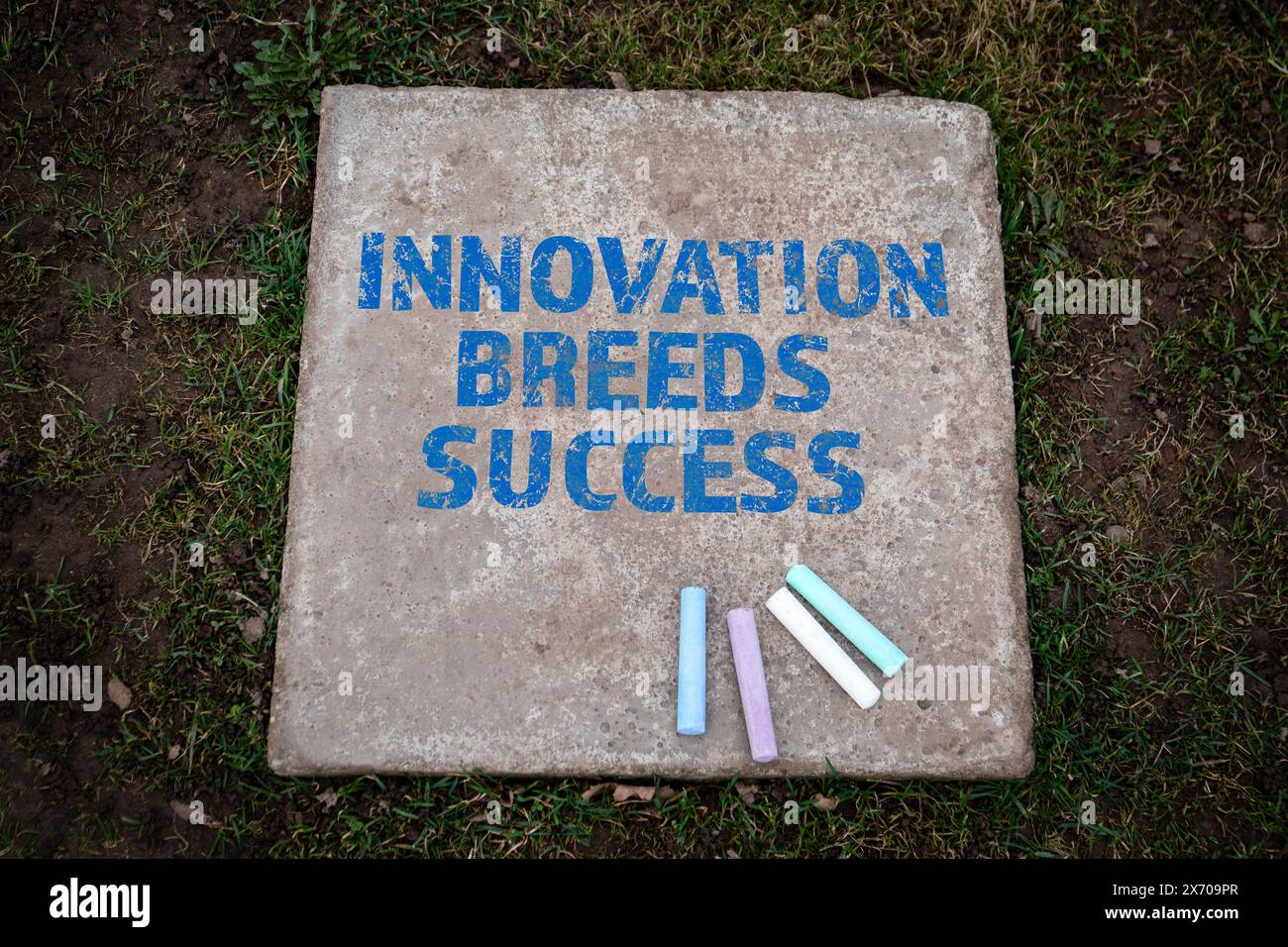 INNOVATION BREEDS SUCCESS. Colored pieces of chalk on a concrete ...