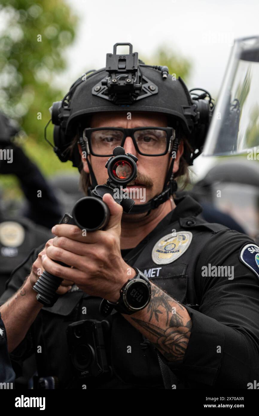 A Santa Ana Police officer points his non-lethal Bean Bag gun at the ...