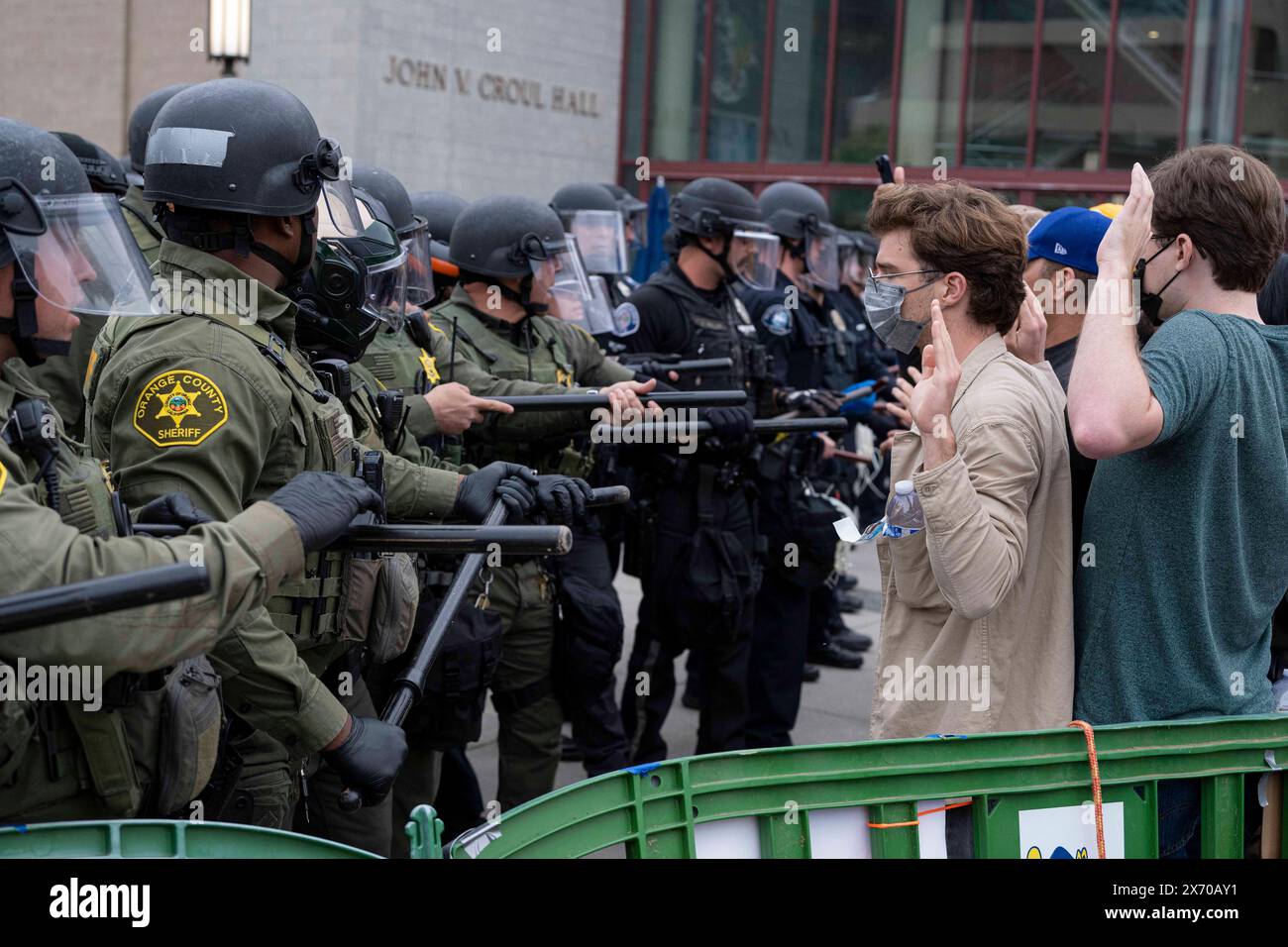 Protesters can been seen with their hands up while swat officers ...