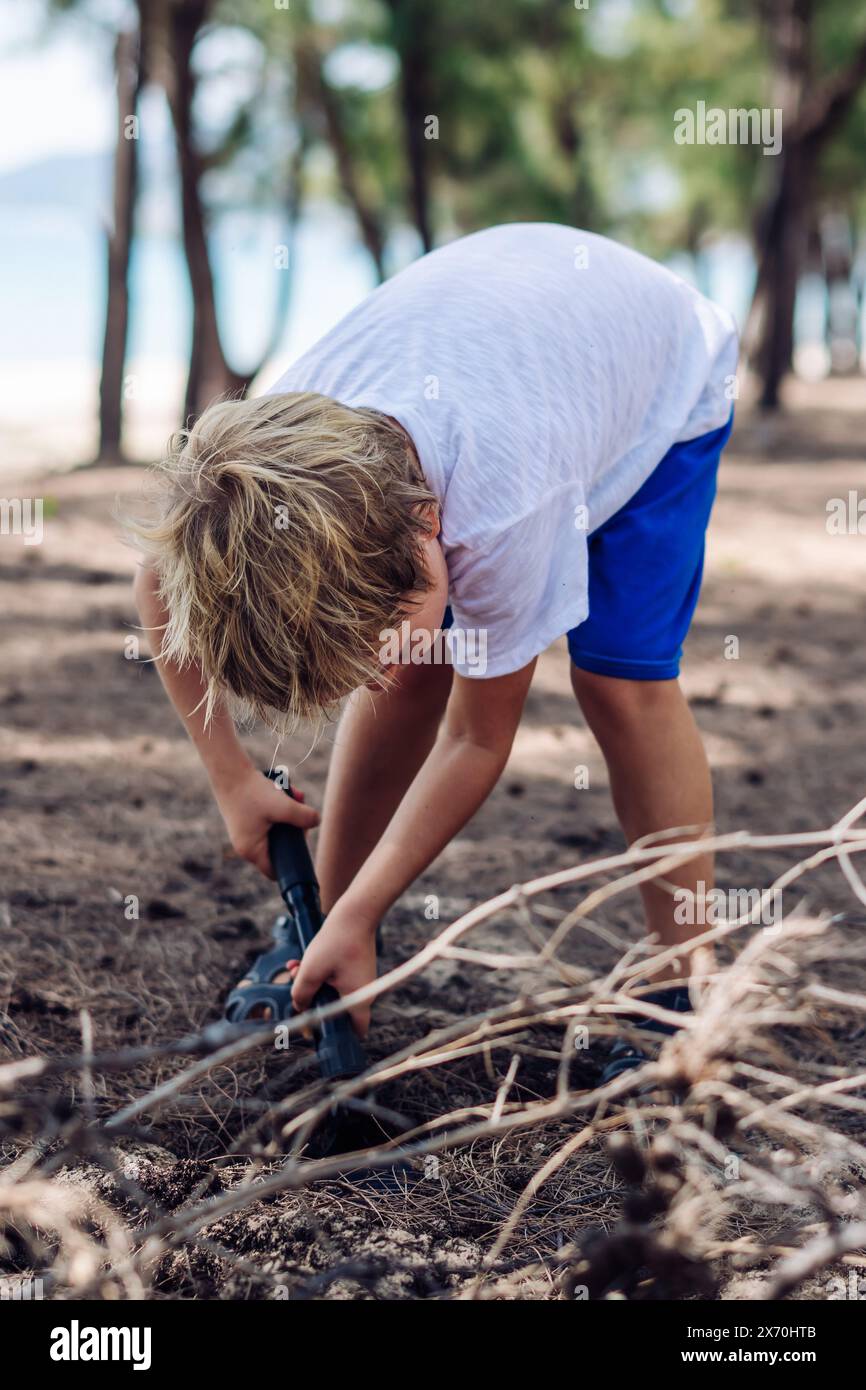Cute boy digging soil in forest near sea beach. Family natural ...