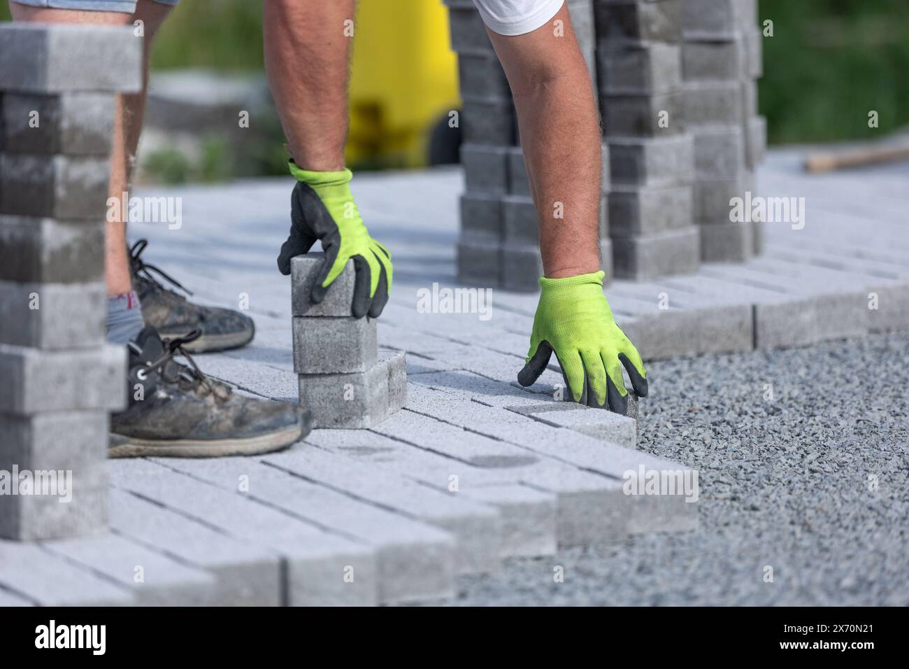 Worker doing new interlocking paving sidewalk made from concrete blocks ...