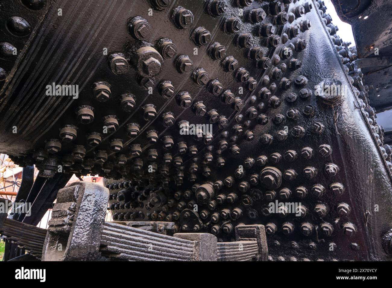 Detail of the many, heavy bolts on a steel, steam, black locomotive. At ...