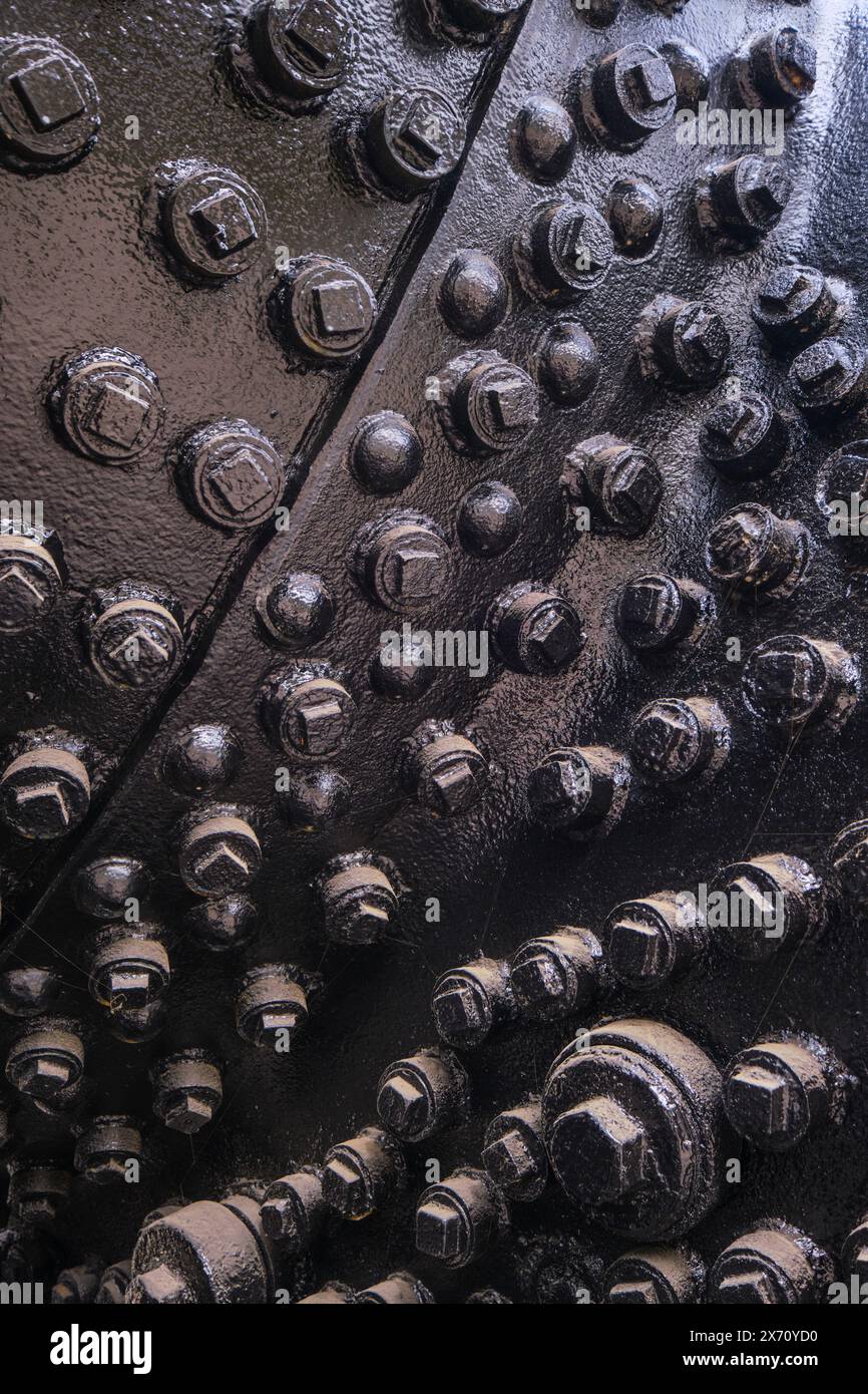 Detail of the many, heavy bolts on a steel, steam, black locomotive. At ...