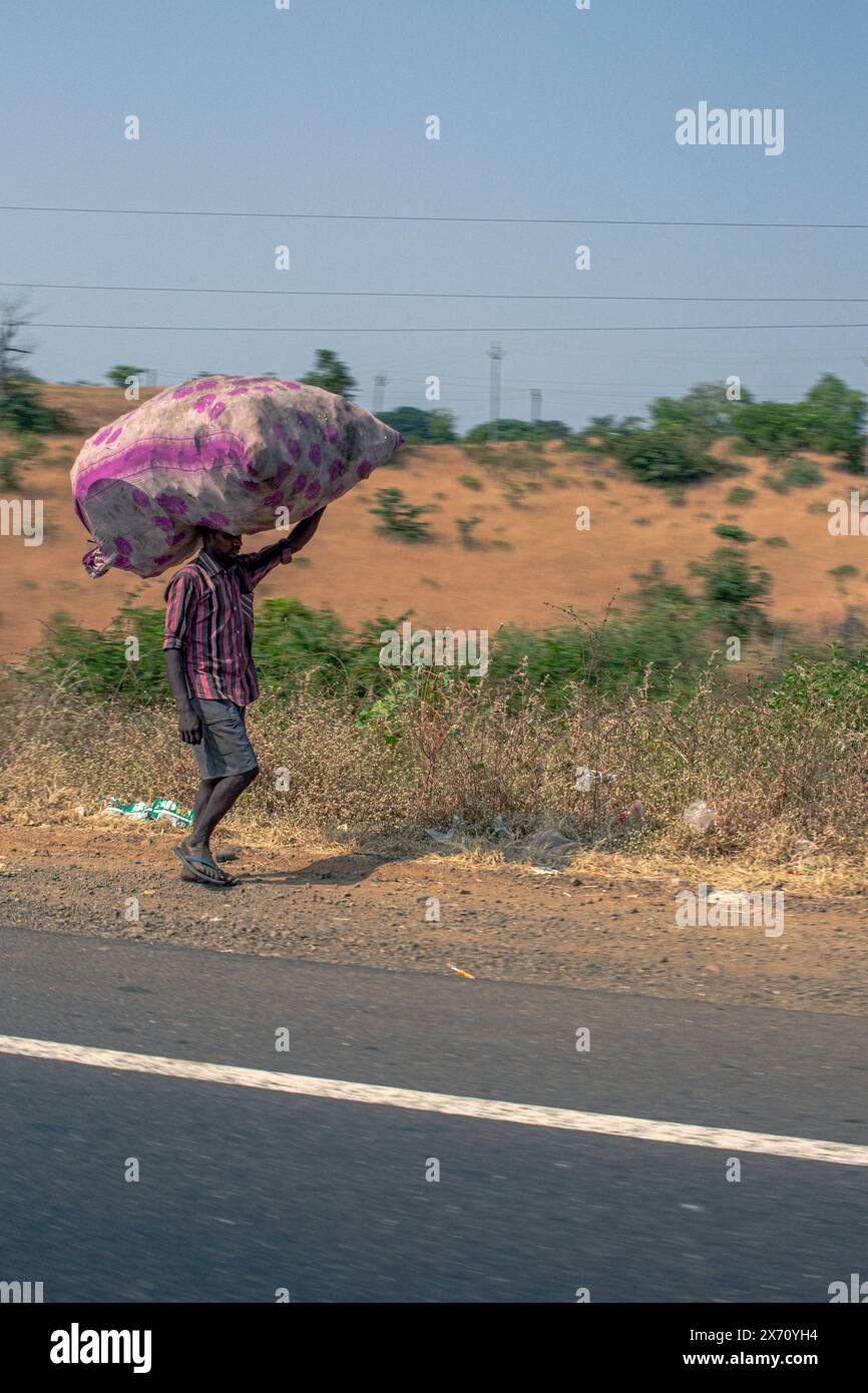 Indian man carrying a load on his head near nashik , maharashtra, india ...