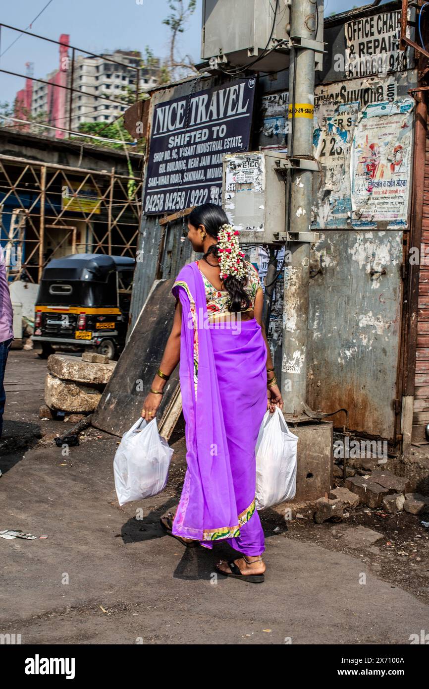 Indian womanwith shopping bags wearing a purple sari walking in in ...