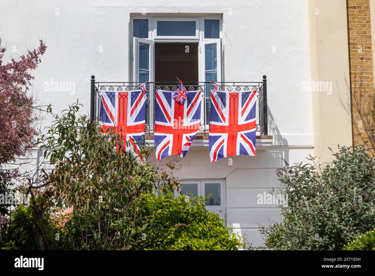 Three Union Jack flags hanging from a house balcony Stock Photo - Alamy