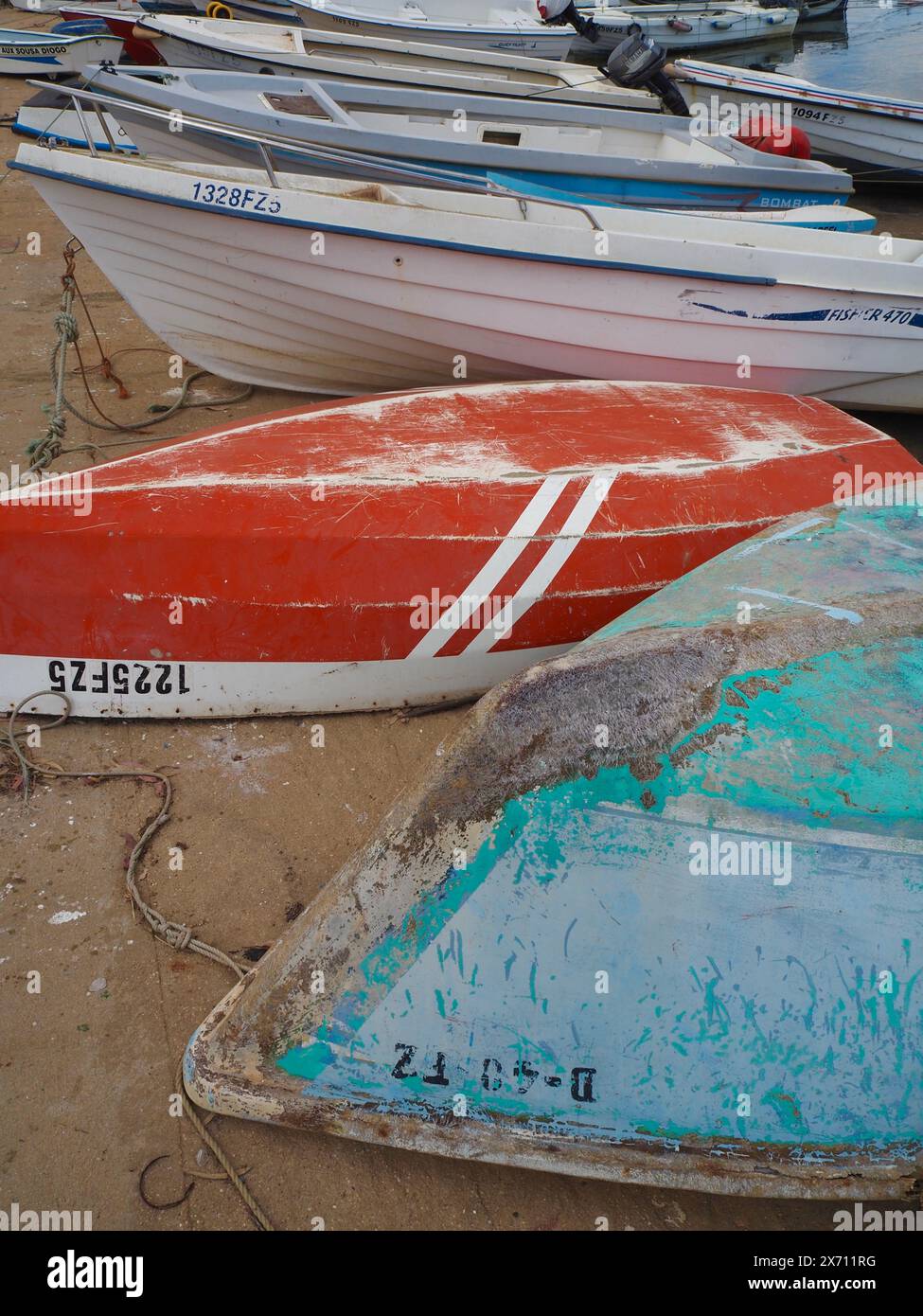 Weatherbeaten red white and blue pleasure boats hauled up on the ...