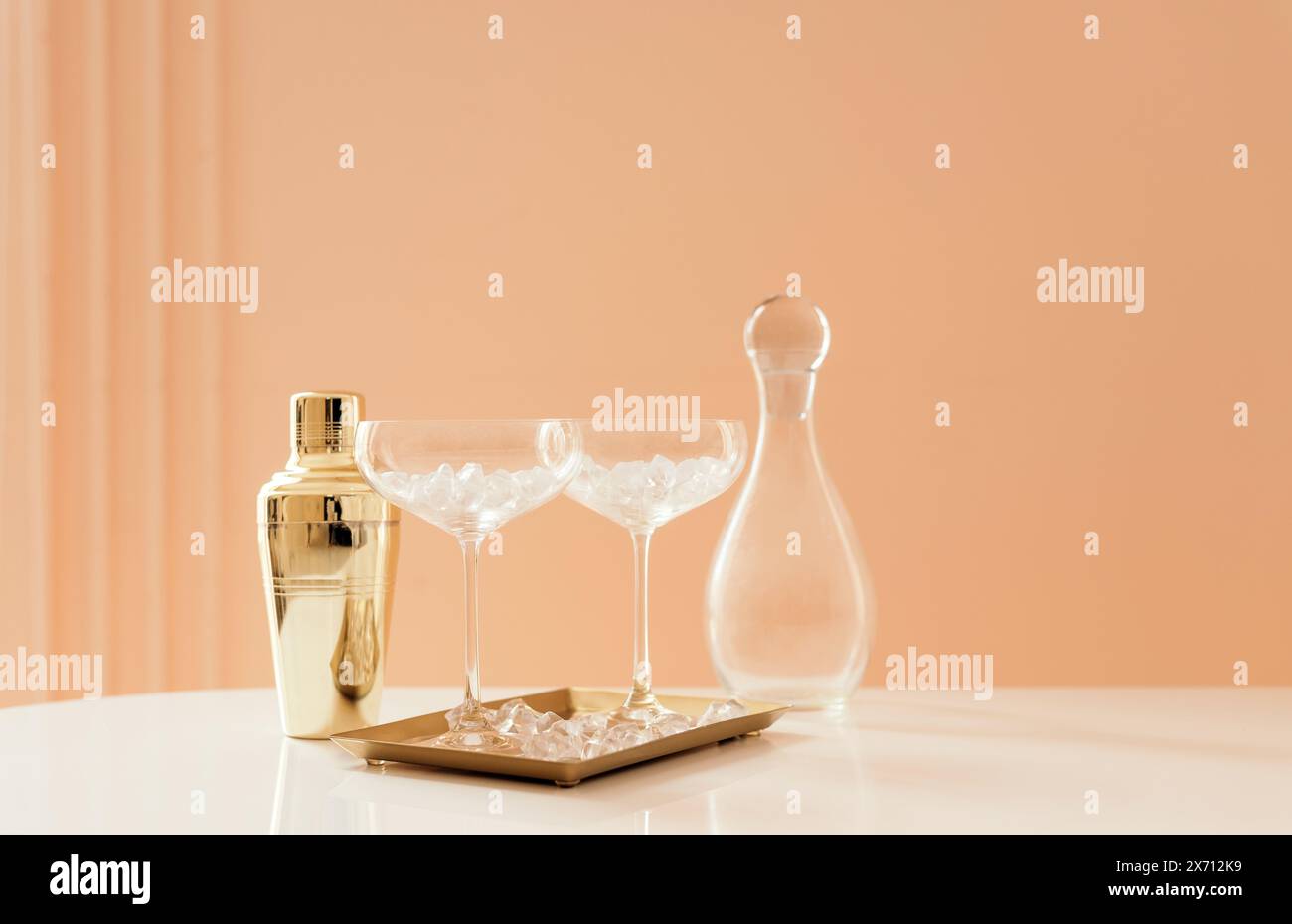 golden shaker, elegant glasses with cocktail, decanter and ice cubes on ...