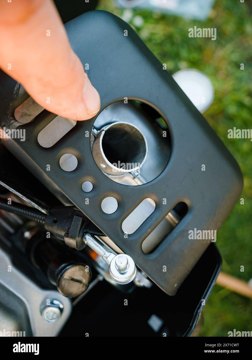 A close-up of a hand adjusting a part of a garden tiller, showing ...