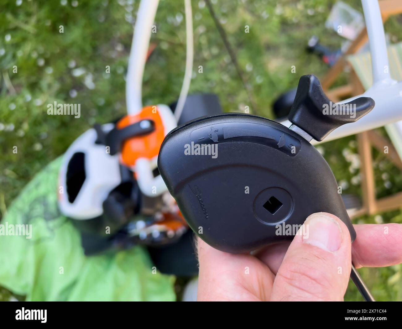 A close-up of a hand adjusting the handle of a garden tiller ...
