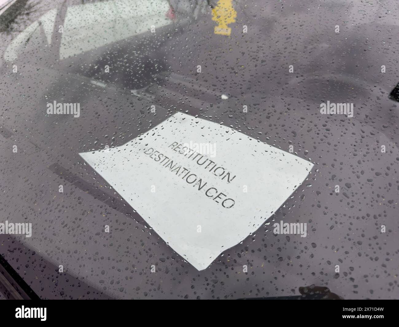 A paper notice with Restitution Destination CEO on a car windshield ...