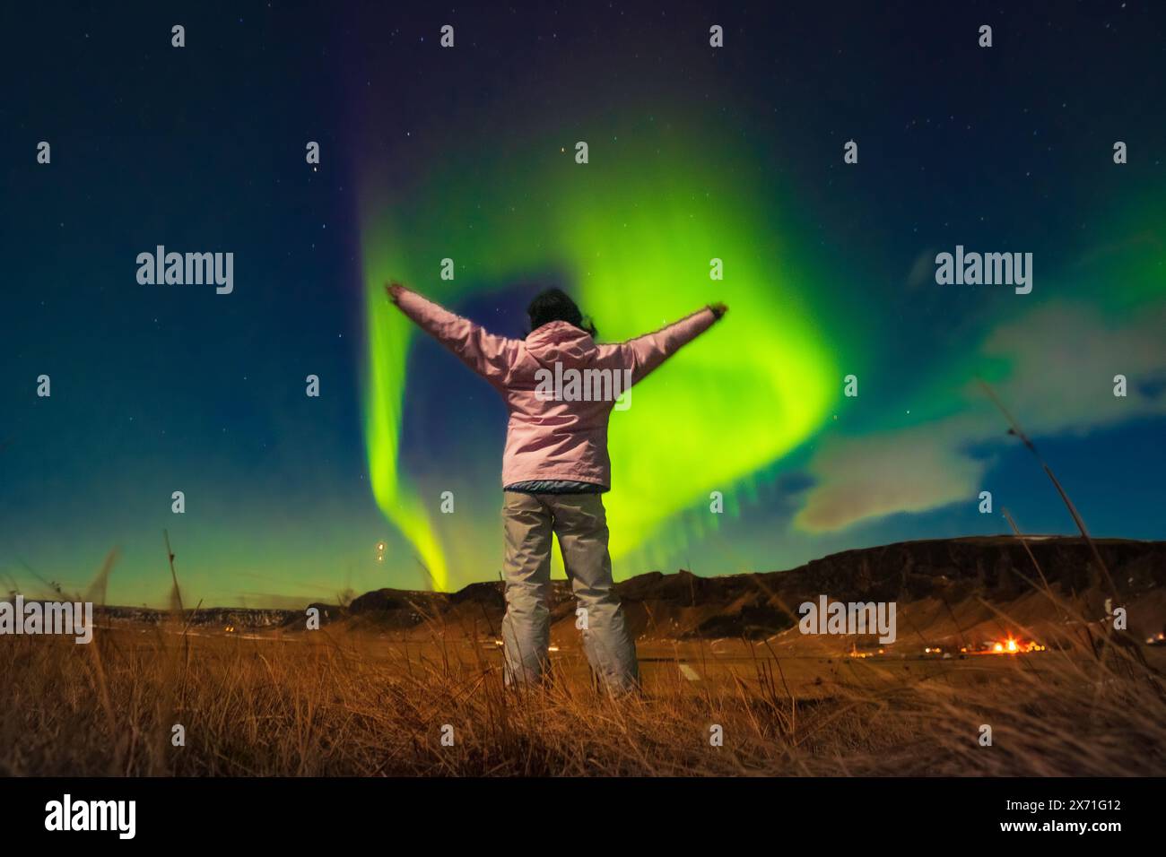 Woman watches the northern lights arms up excited joyful in Iceland ...