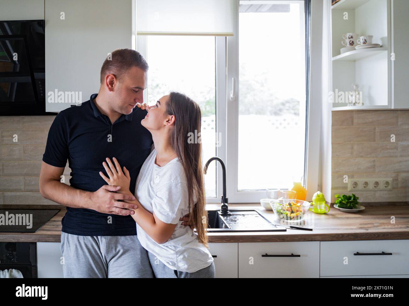 A loving married couple in a modern kitchen, standing and hugging Stock ...