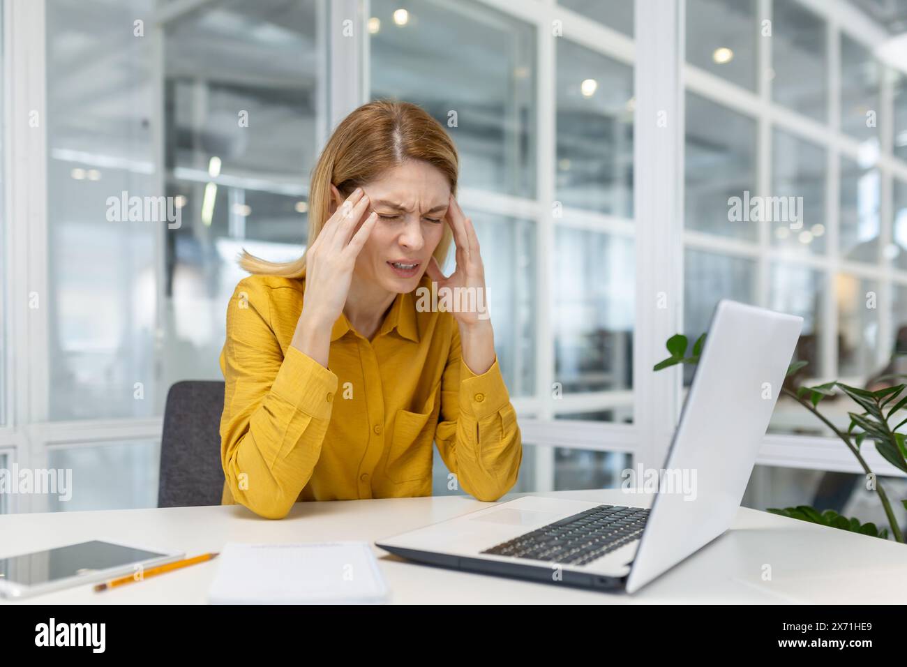 Businesswoman feeling stressed and overwhelmed at her desk in a modern ...