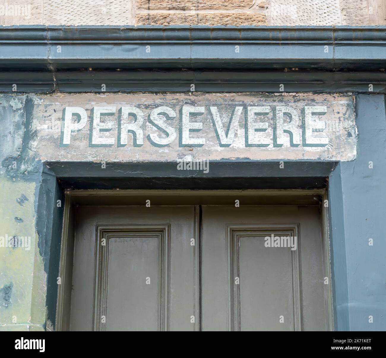 PERSEVERE - a ghost sign revealed above a door Stock Photo - Alamy