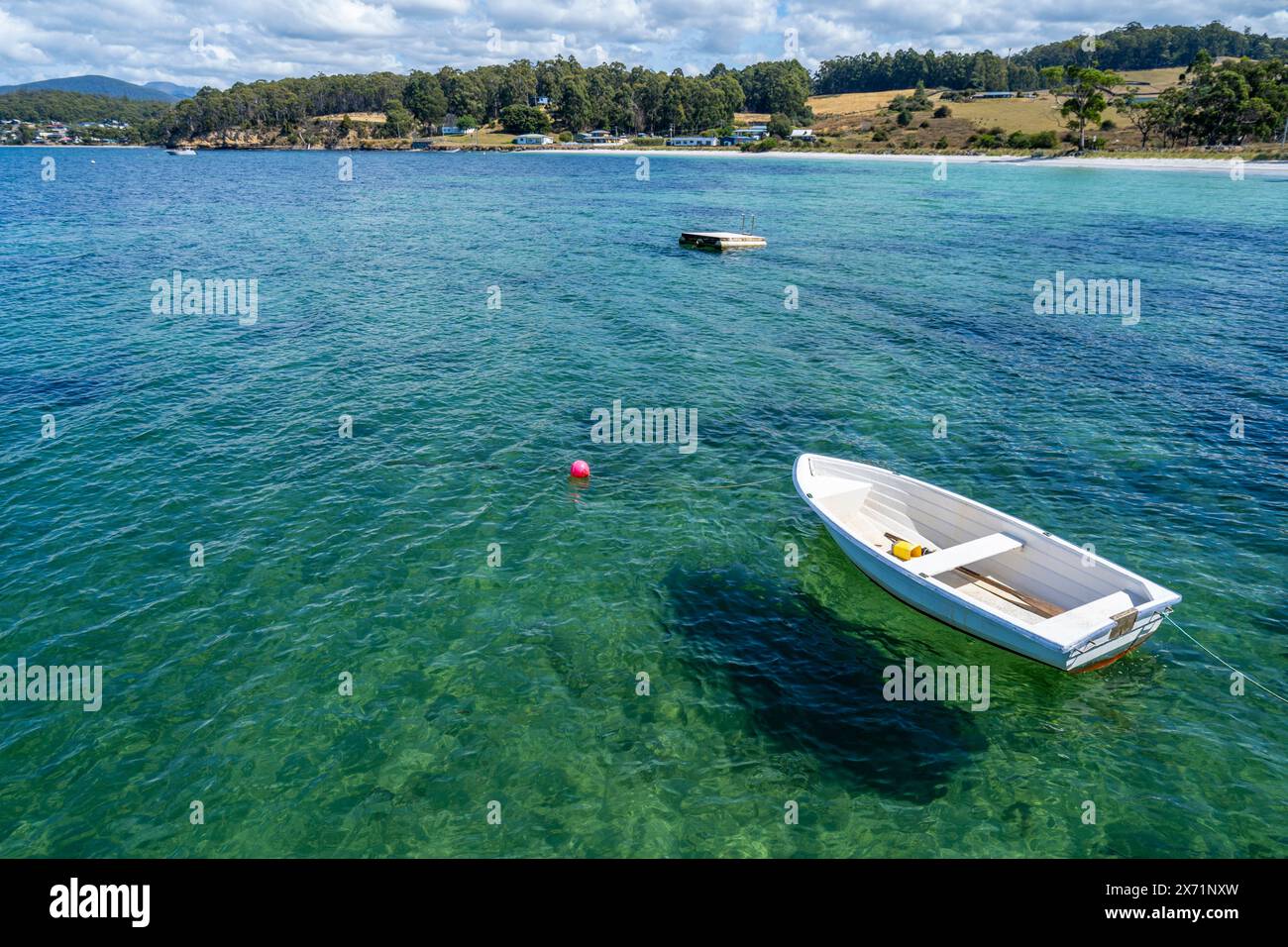 White dingy at anchor in clear water at Southport, Southern Tasmania ...