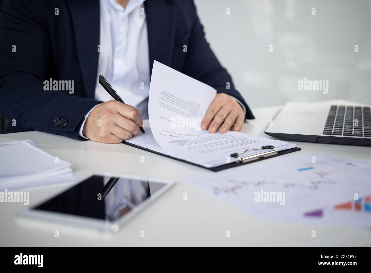 Asian mature man in a business suit signing important documents at an ...