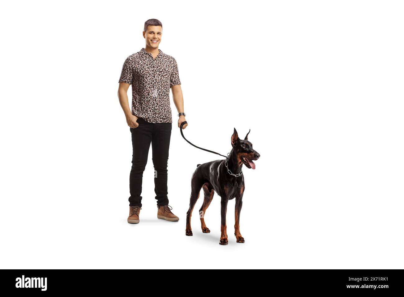 Full length portrait of a young man posing with a doberman dog on a ...