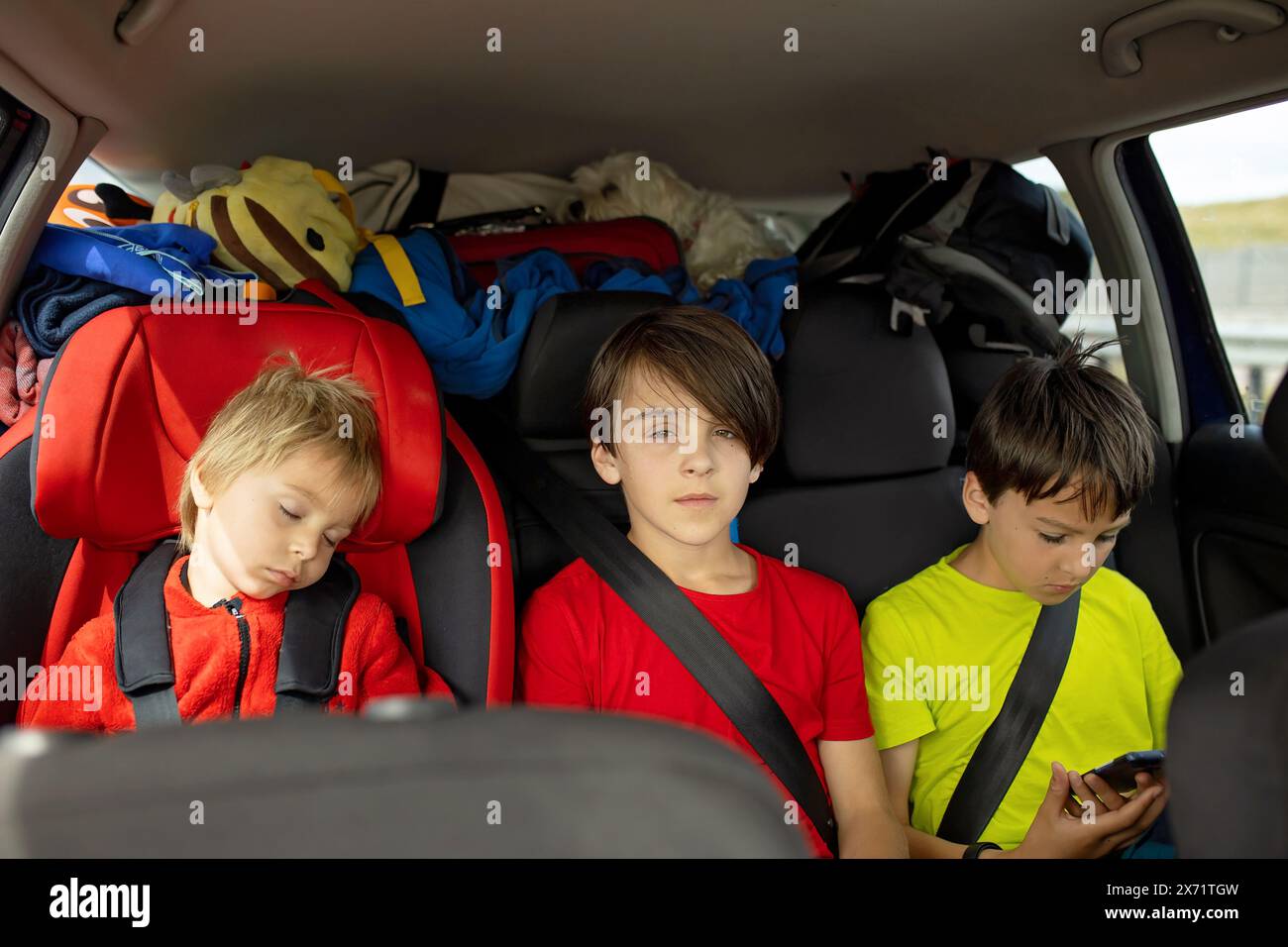 Three boys in car seats, traveling in car, sleeping and playing on ...