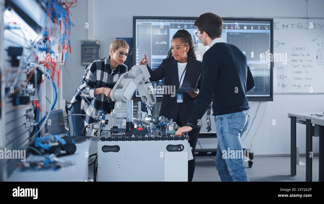 In Robotics Development Laboratory: Black Female Teacher and Two Students Work With Prototype of ...