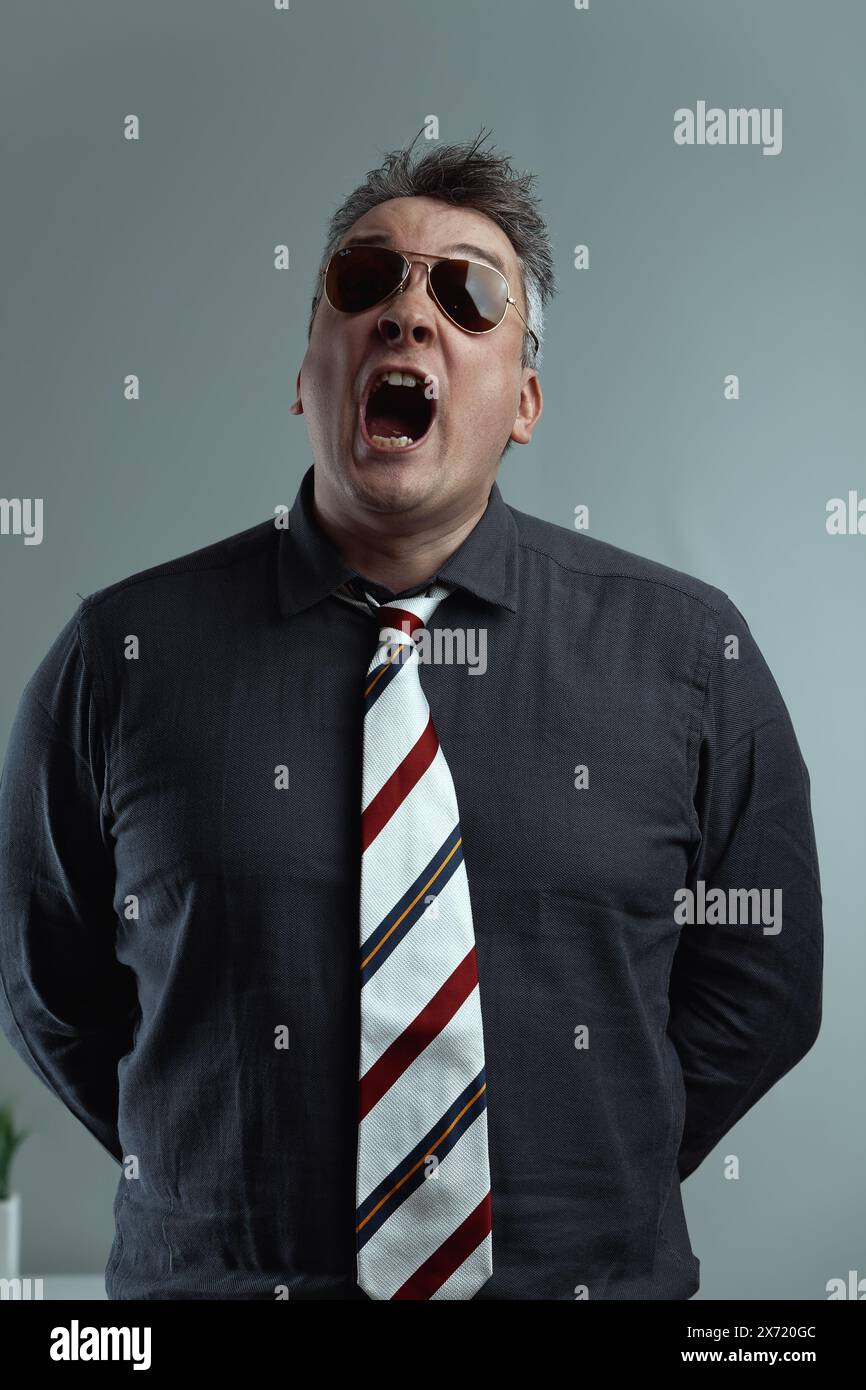 middle-aged man wearing sunglasses and a striped tie yells, possibly ...