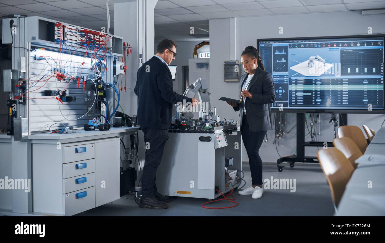 Diverse Colleagues Standing Near Table With Robot Arm And Discussing ...