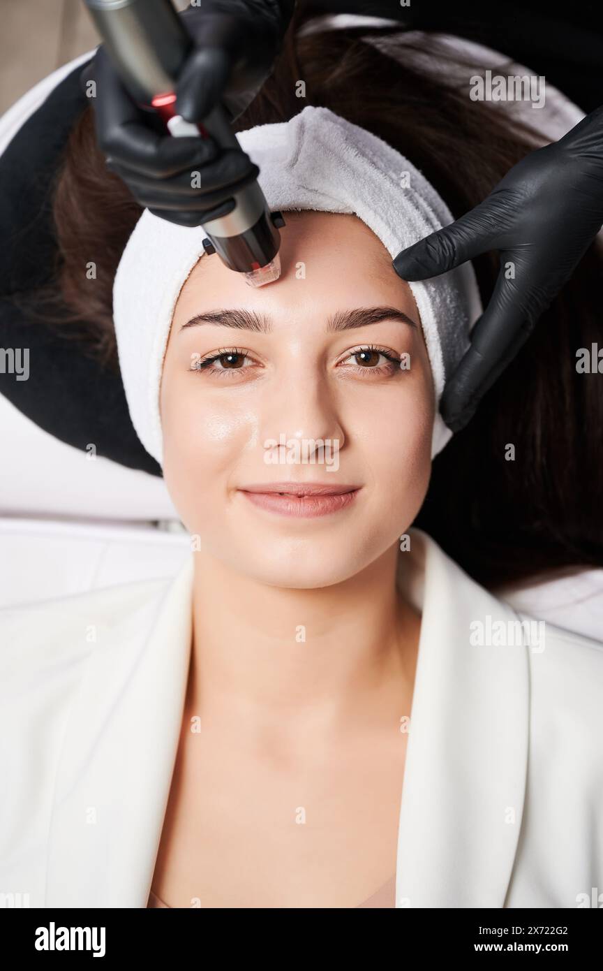 Professional cosmetologist performing rejuvenating radiofrequency hi ...
