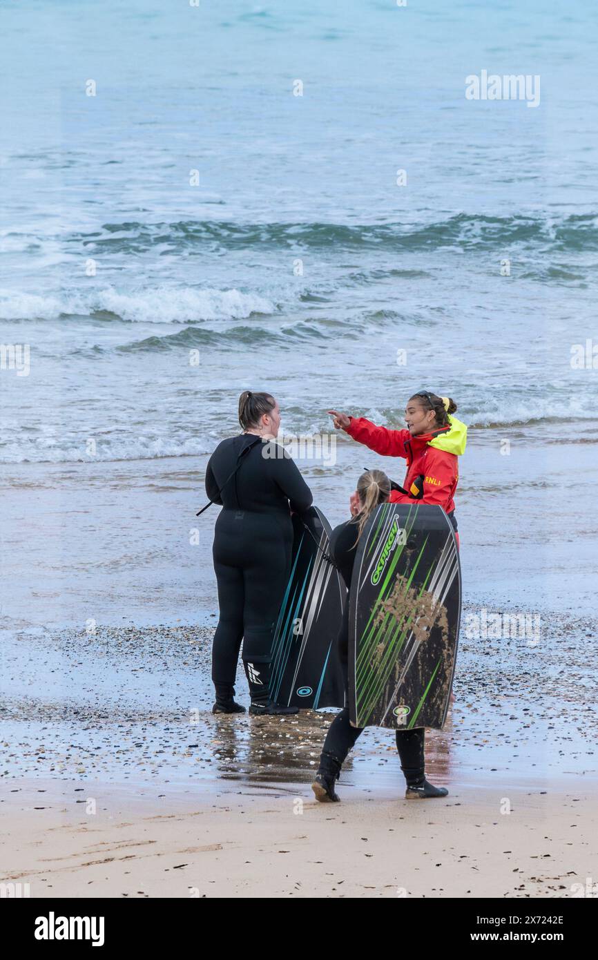 Female bodyboarders talking to a female RNLI Lifeguard on Fistral beach ...