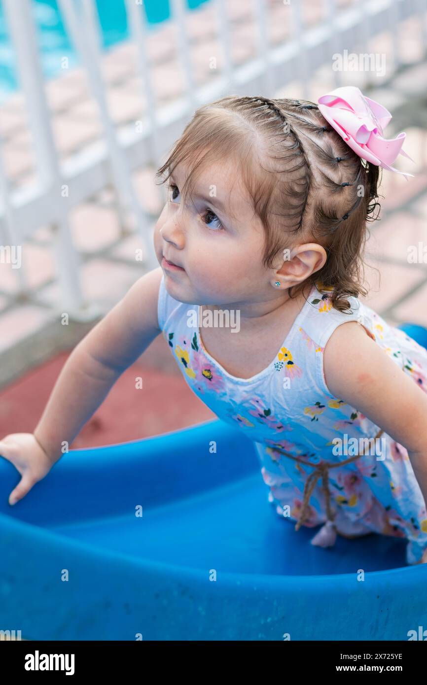 little latina girl climbing on the small slippery slide on the opposite ...