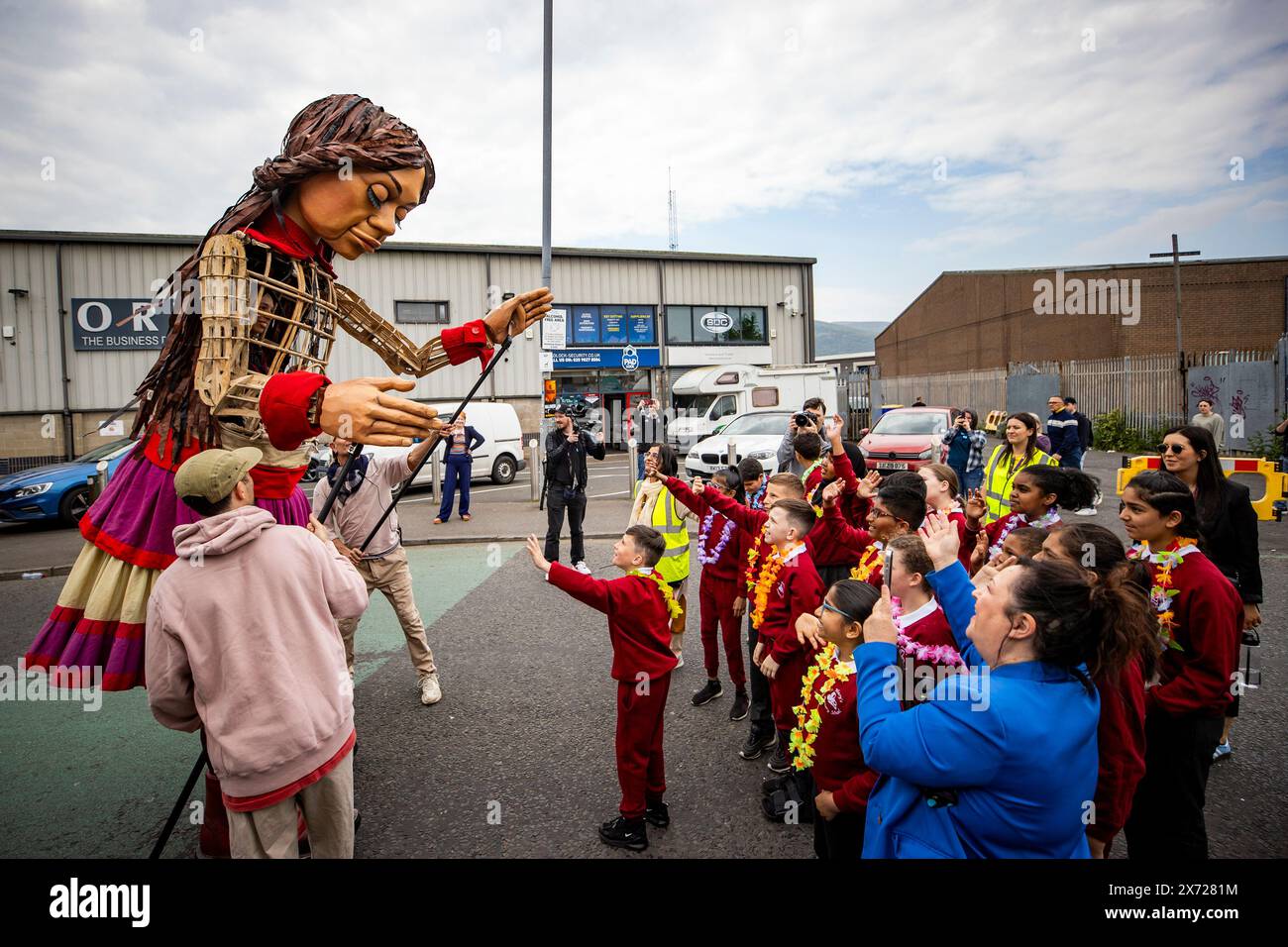Local school children wave at Little Amal, a 12-foot tall puppet of a ...