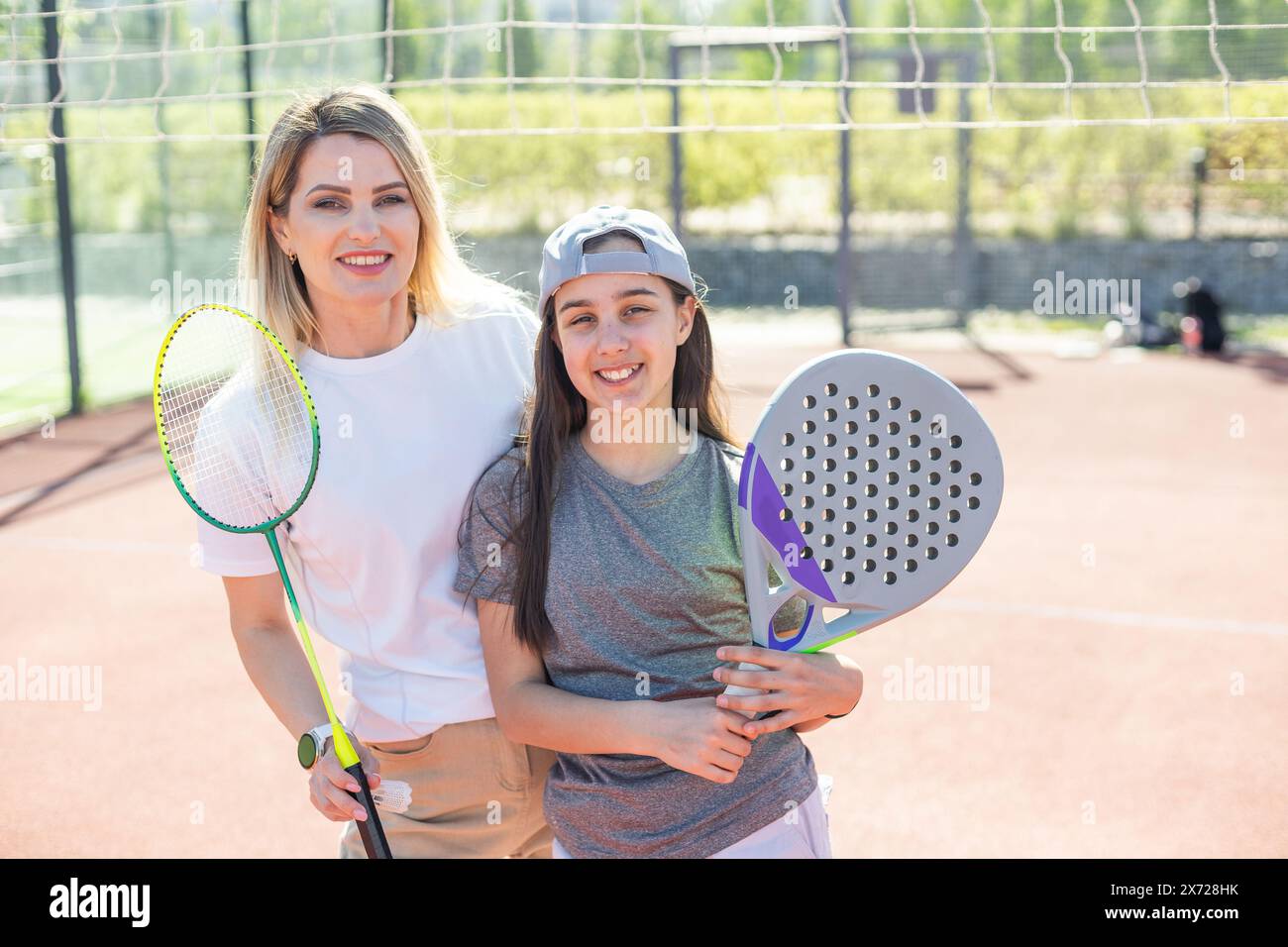 Happy caucasian mother and daughter playing padel tennis and badminton ...