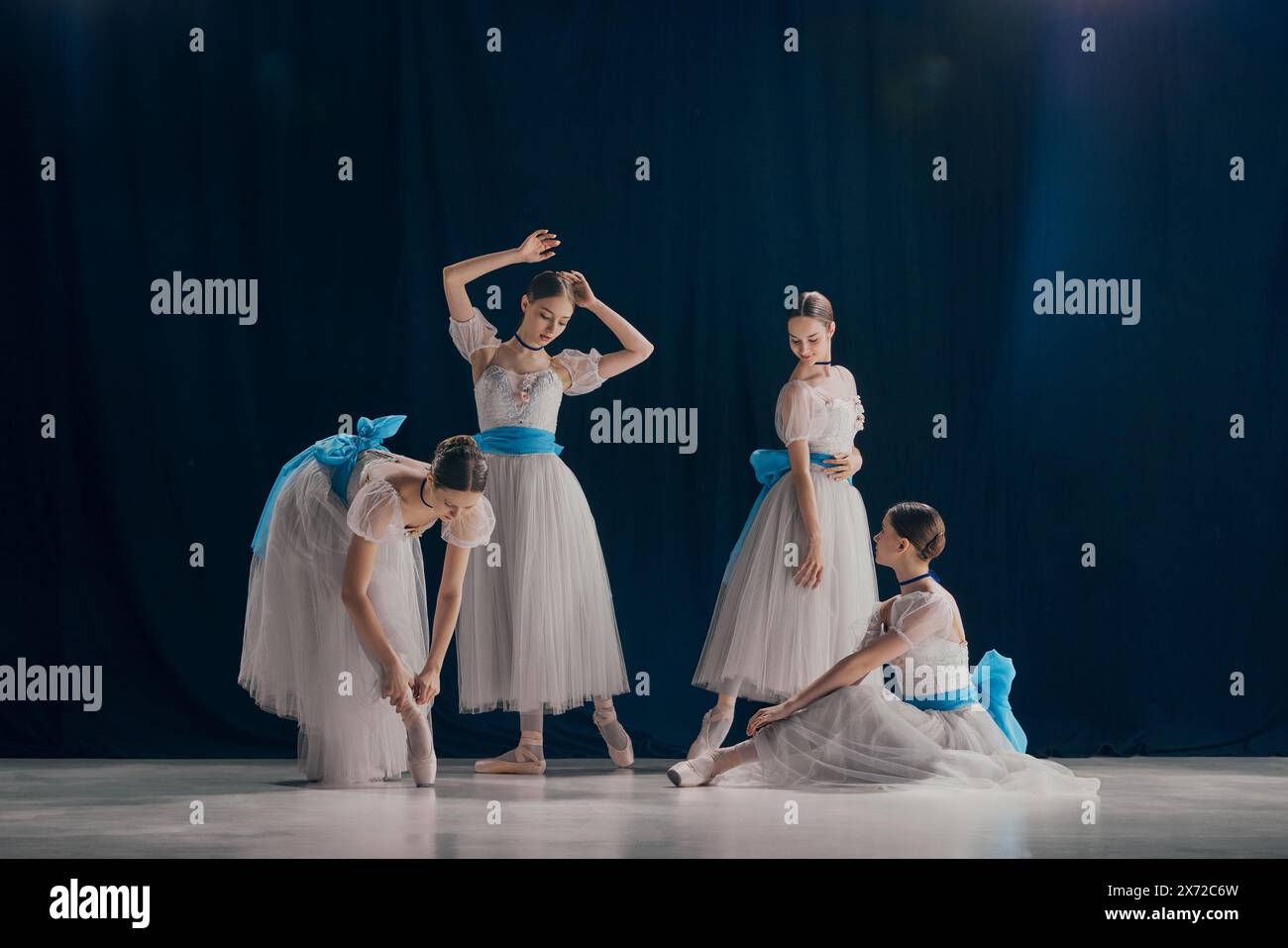 Four young tender ballerinas dressed in delicate white tutus with blue ...