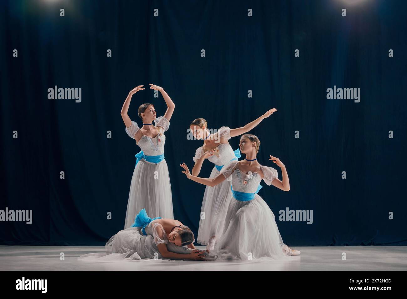 Four ballerinas, poised in white tutus with blue sashes, exhibit their ...