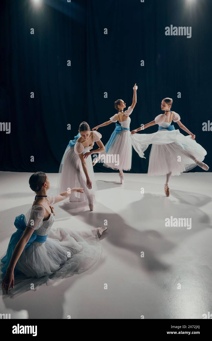 Four ballet dancers in flowing white costumes with blue ribbons ...