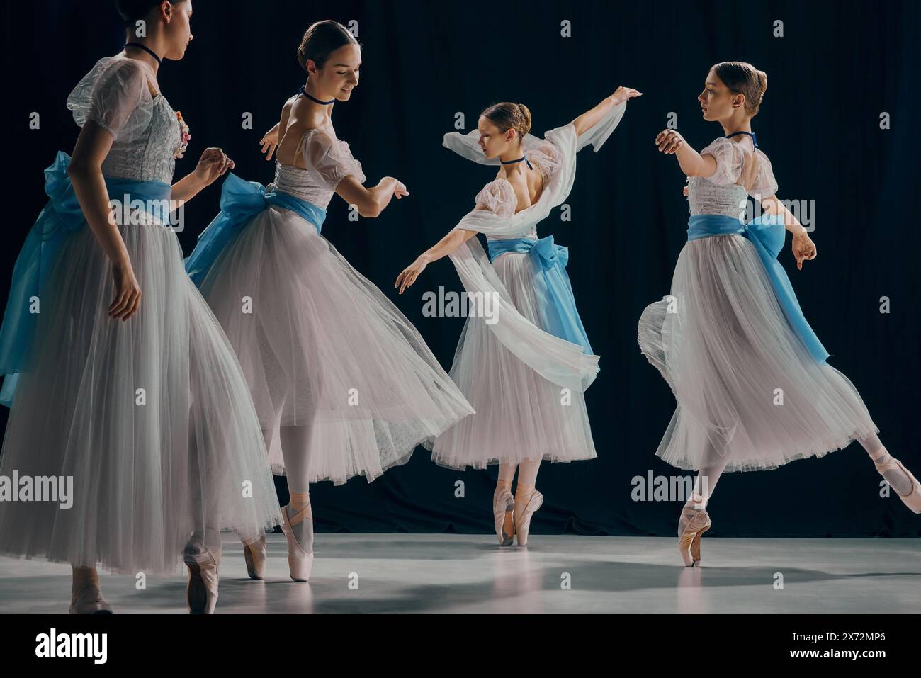 Quartet of young ballet dancer, in flowing white costumes with blue ...