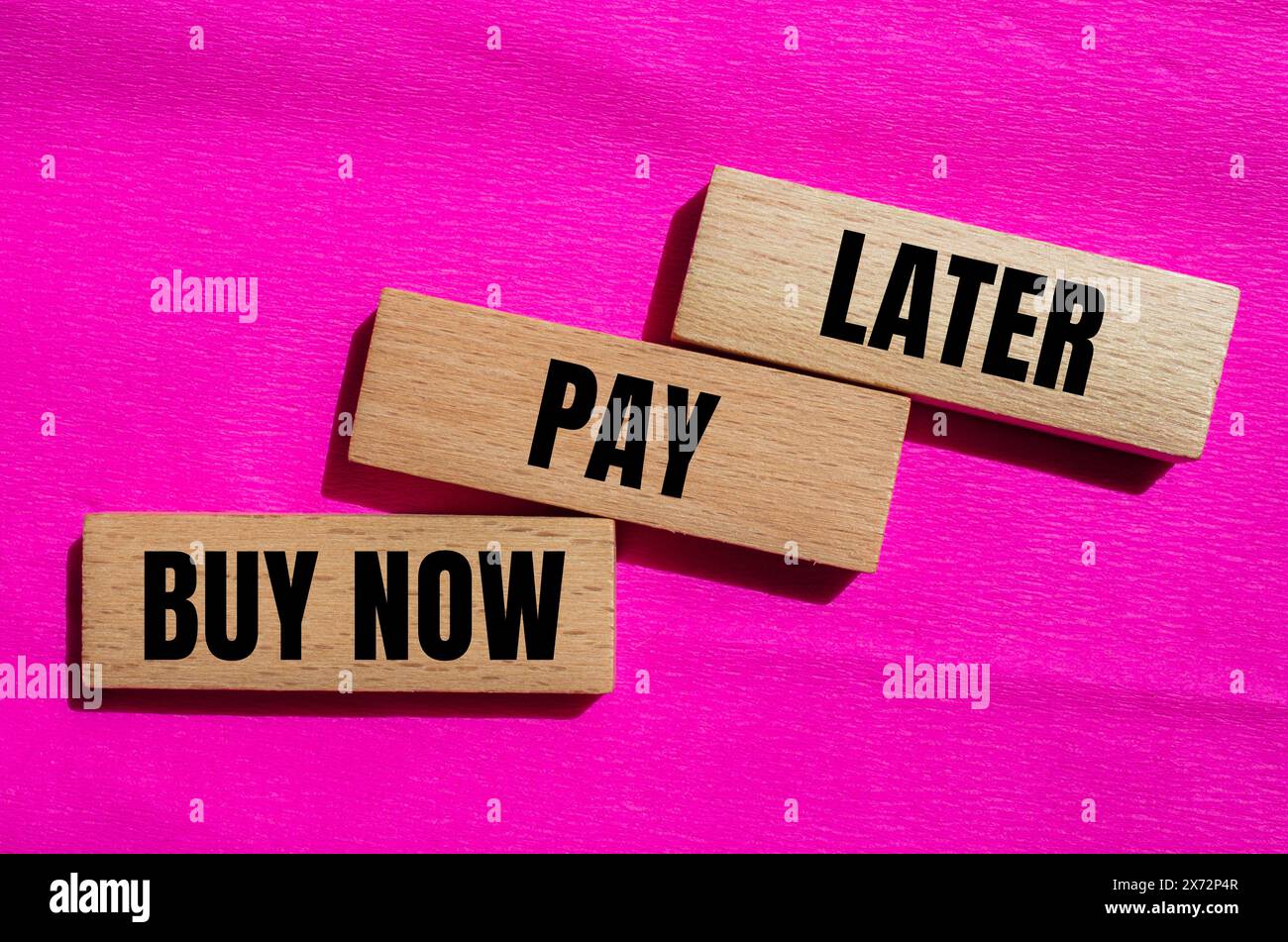 Buy now pay later words written on wooden blocks with pink background ...